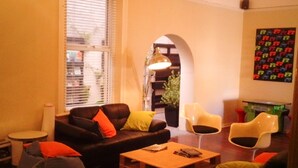 Uma sala de estar aconchegante com um sofá, duas poltronas, uma mesa de centro e uma estante de livros.