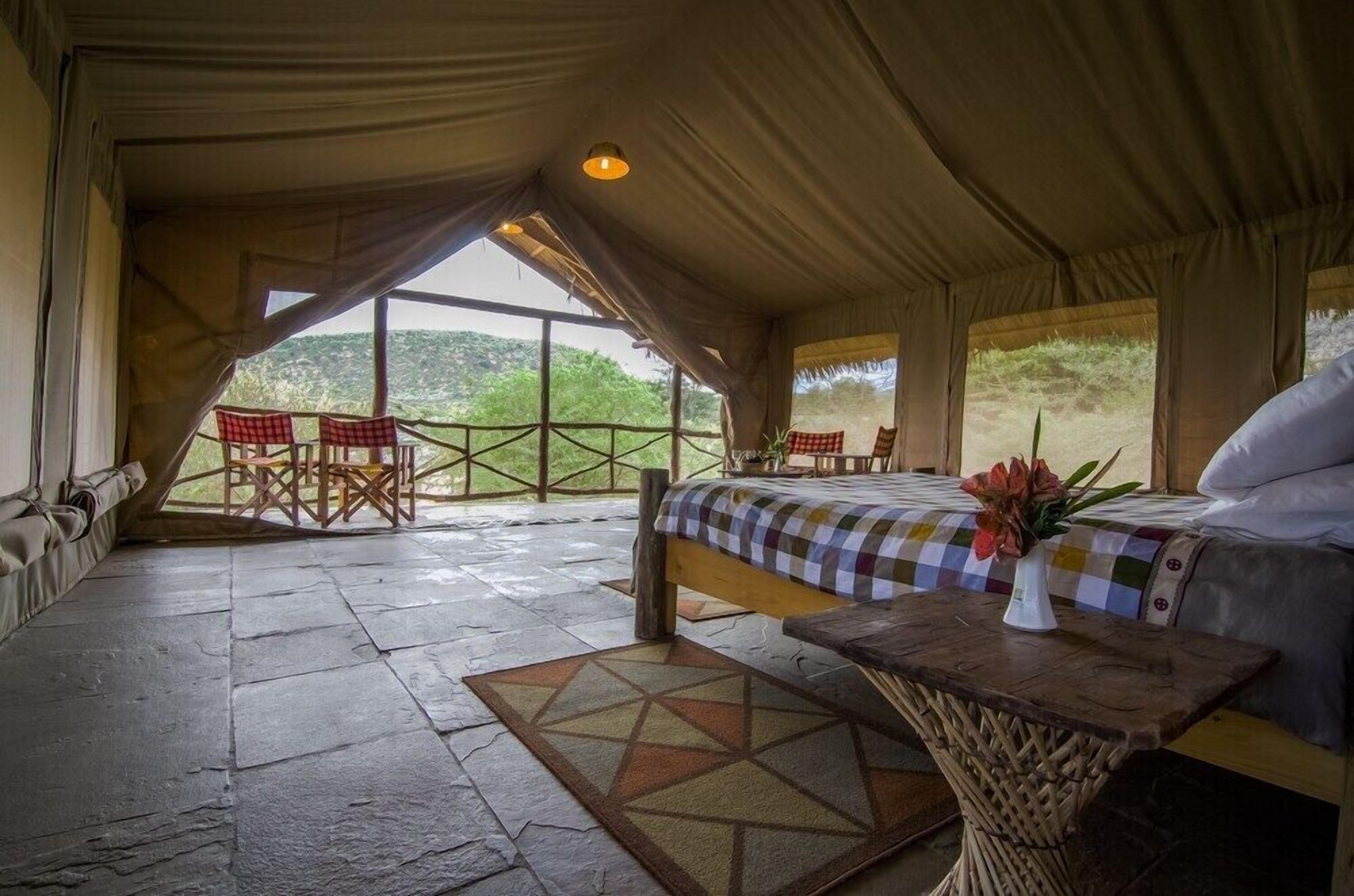 Alojamento em tenda com uma cama, uma mesa e uma cadeira.