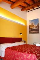 Quarto de hotel com cama, mesa de cabeceira, abajur e um quadro na parede.