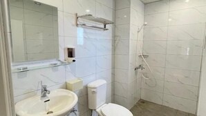 Um banheiro moderno com pia, vaso sanitário e chuveiro.