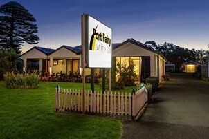 Um hotel chamado Port Fairy Motor Inn, com entrada bem iluminada, cerca de piquete e jardim paisagístico.