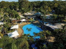 Um resort com uma piscina grande, palmeiras e vários edifícios.