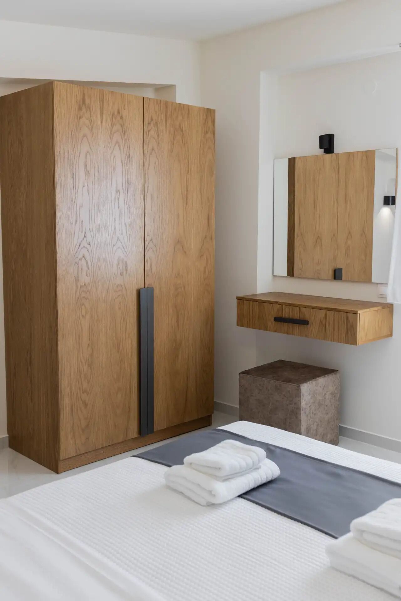 Quarto com guarda-roupa espaçoso, mesa de cabeceira, espelho e uma cama.