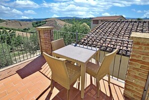 Varanda com mesa e cadeiras, com vista para uma paisagem montanhosa.