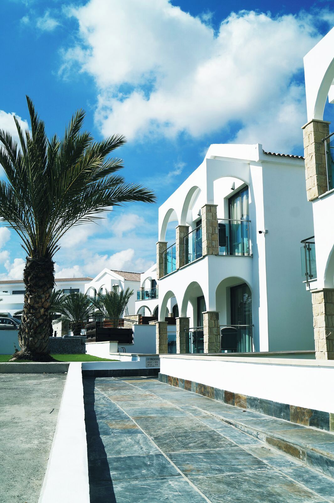 Um edifício moderno com paredes brancas, varandas em arco e base de pedra.