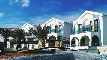 Um resort moderno com edifícios brancos, uma ponte e uma piscina.