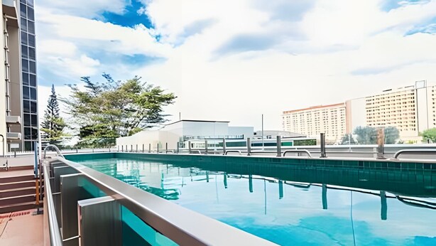 Piscina com vista clara para os edifícios e árvores ao redor.