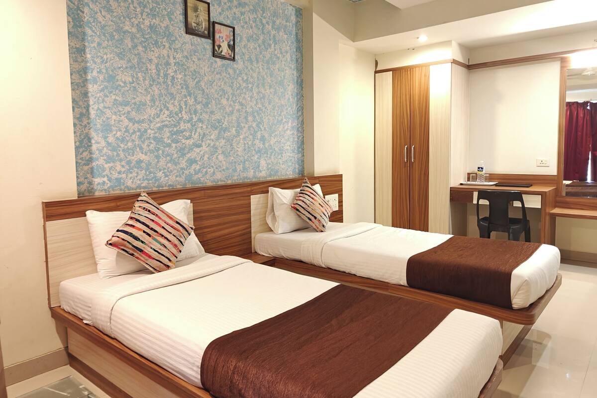 Quarto de hotel com duas camas, uma escrivaninha e um guarda-roupa.
