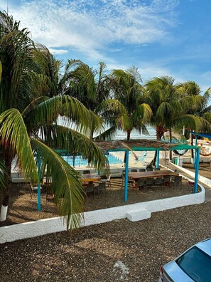 Uma área à beira da piscina com palmeiras, piscina e mobiliário de exterior.