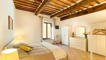Quarto com cama, cômoda, radiador e janela.