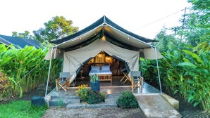Acomodação em tenda com cama, área de estar e uma pequena mesa.
