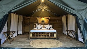 Uma tenda com cama, paredes de madeira e um tapete circular.