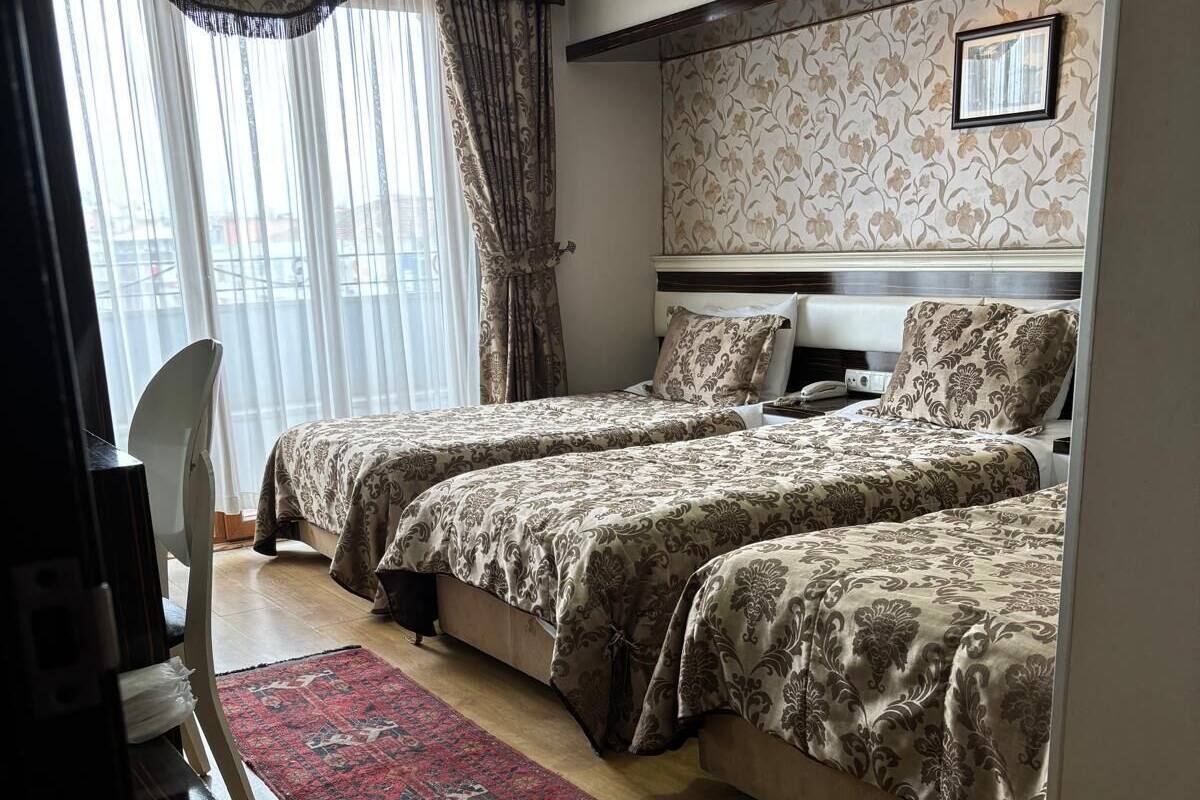 Quarto de hotel com duas camas, uma escrivaninha e uma cadeira.