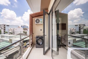 Uma varanda com máquina de lavar, porta de correr de vidro e vista para a cidade.