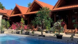 Uma área à beira da piscina com piscina e edifícios de madeira com telhados vermelhos.