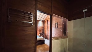 Interior em madeira com banheiro visível, uma cama e piso estampado.