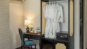 Quarto de hotel com escrivaninha, uma cadeira, roupão pendurado em um porta-roupões e micro-ondas.