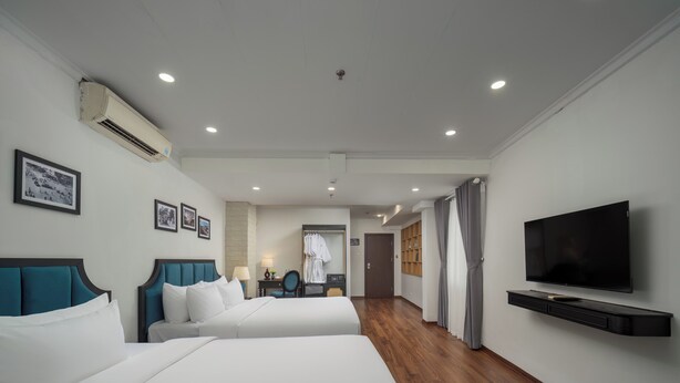 Quarto de hotel com duas camas, televisão, secretária e guarda-roupa.