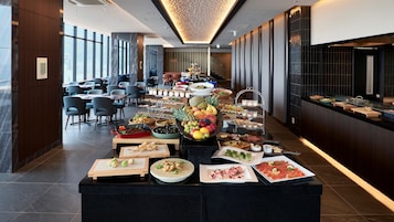 Espaço de buffet com diversas opções de comida, assentos dispostos e design de interiores moderno.