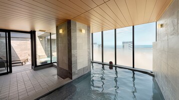 Uma área interna de piscina moderna com vista clara para a praia e o oceano.