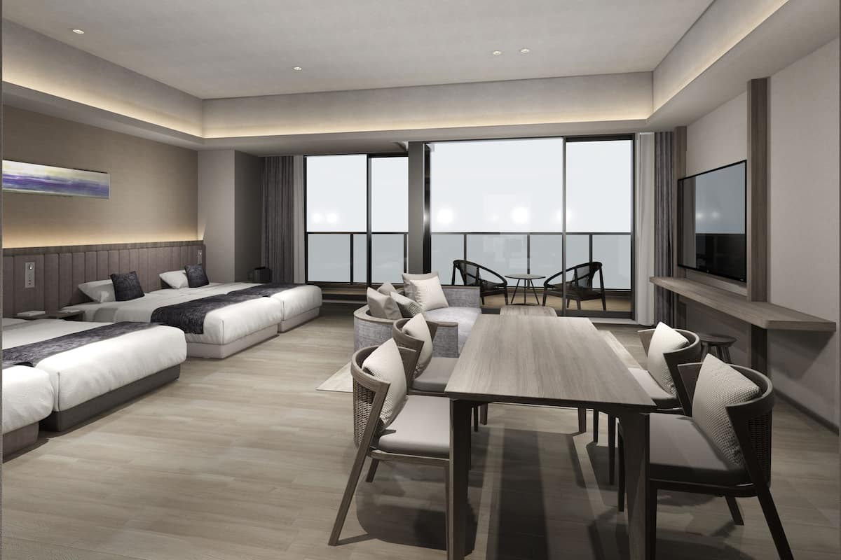 Quarto de hotel moderno com uma cama grande, uma mesa de jantar e uma TV.