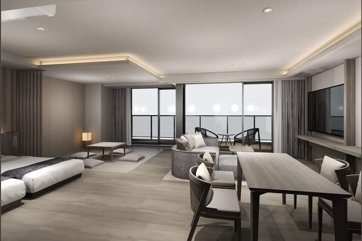 Quarto de hotel moderno com uma cama grande, área de jantar e televisão.