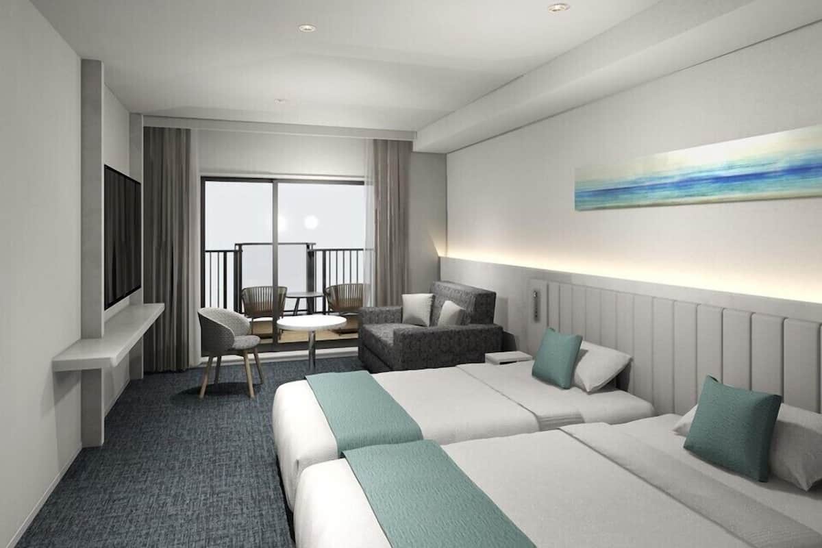 Quarto de hotel com duas camas, área de estar com mesa e cadeiras, televisão e uma janela grande.