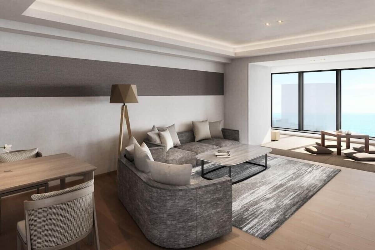 Uma sala de estar moderna com um sofá curvo, uma mesa de centro e uma área de jantar com uma mesa e cadeiras de madeira.