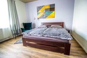 Um quarto com uma cama de madeira, uma cadeira verde e uma pintura na parede.