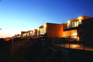 Um hotel moderno com vários edifícios interligados, área de estar ao ar livre e uma parede de pedra.
