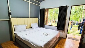 Uma cama de solteiro com cabeceira, roupa de cama branca e janela com cortinas.