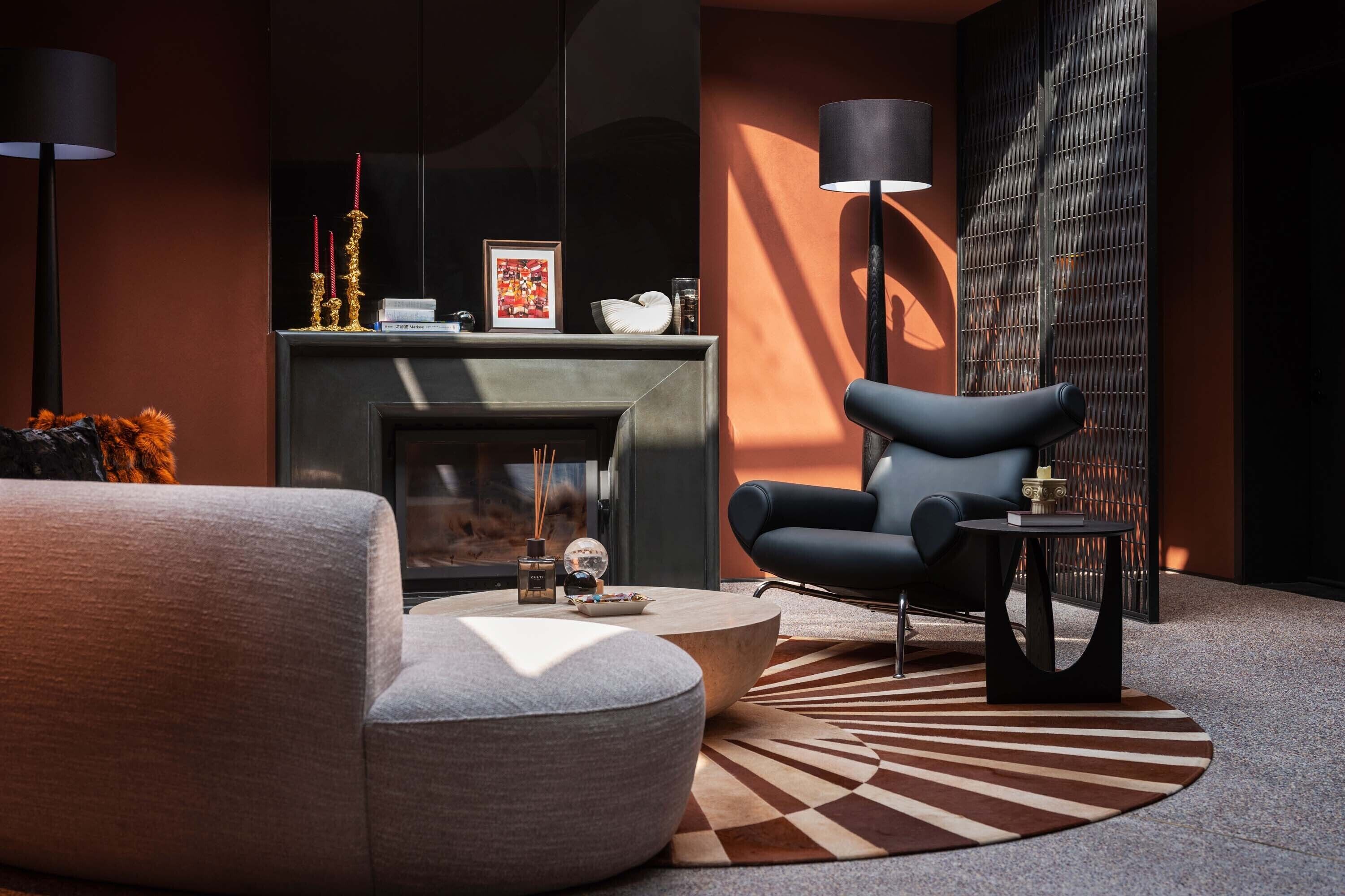 Uma sala de estar moderna com lareira, sofá, poltrona e mesa de centro.