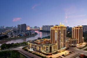Um hotel com uma torre imponente, um rio ao fundo e uma ponte.
