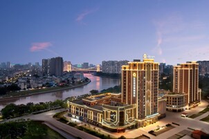 Um hotel com uma torre imponente, um rio ao fundo e uma ponte.