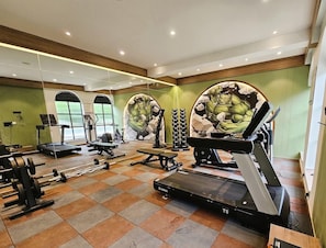 Academia com esteiras, aparelhos de musculação e espelho.