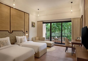 Quarto de hotel com duas camas, um sofá, uma mesa de jantar e uma televisão.