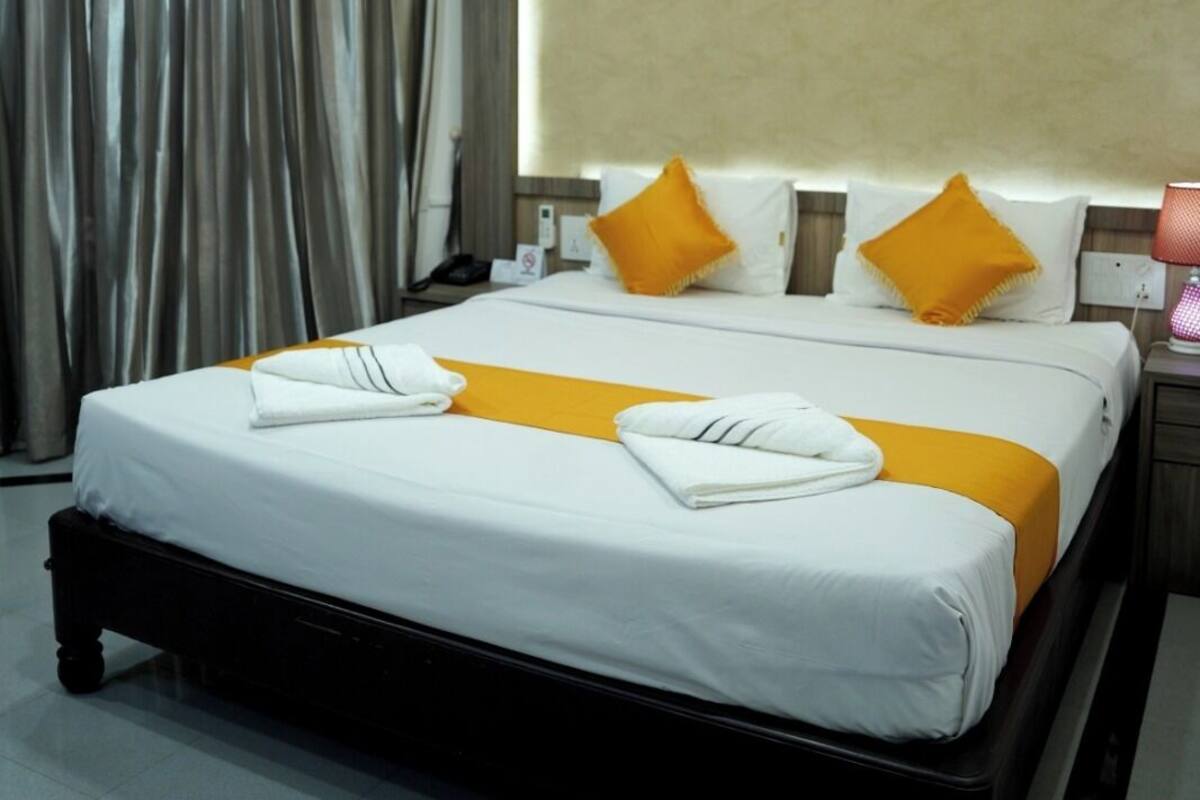 Quarto de hotel com uma cama grande, um ventilador de teto e uma mesa de cabeceira com abajur.