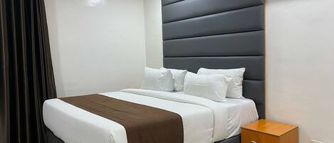 Quarto moderno com cama, mesa de cabeceira e cabeceira escura.