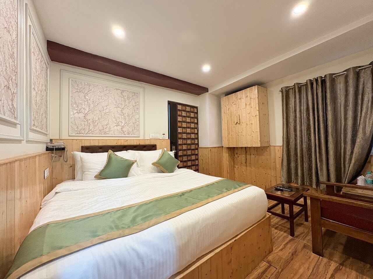 Quarto bem arrumado com cama de madeira, uma mesinha e um guarda-roupa.