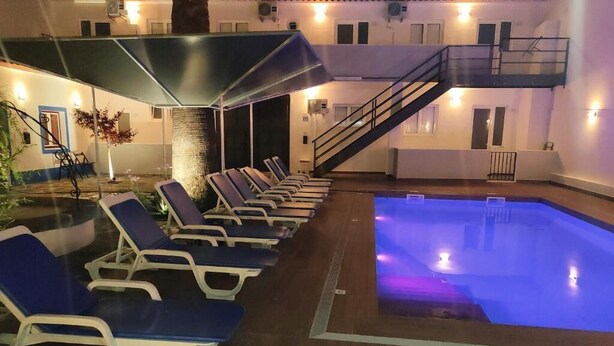 Uma área de piscina com espreguiçadeiras e uma escadaria que dá acesso a um andar superior.