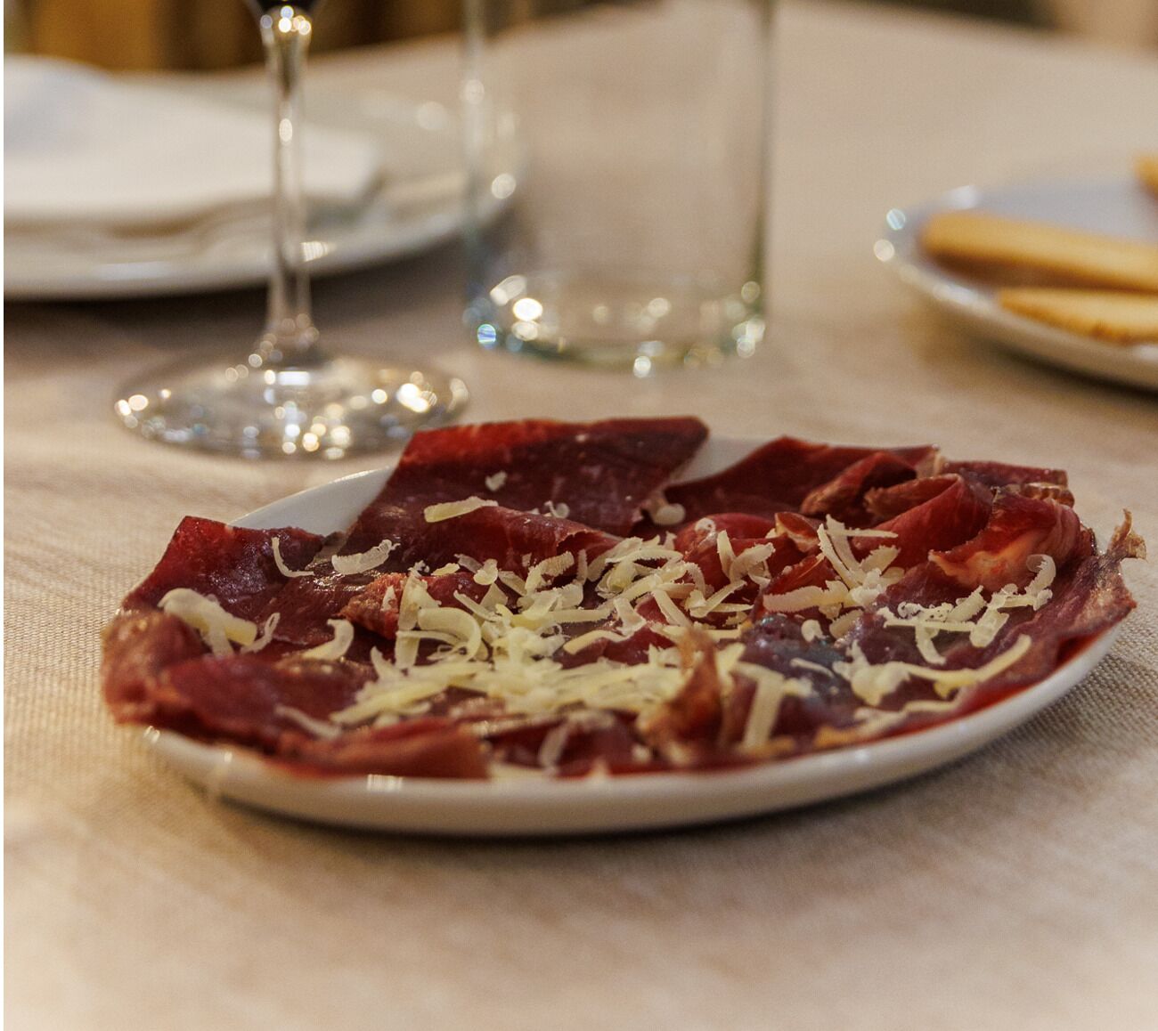 Um prato de carne fatiada coberta com queijo ralado sobre uma mesa.