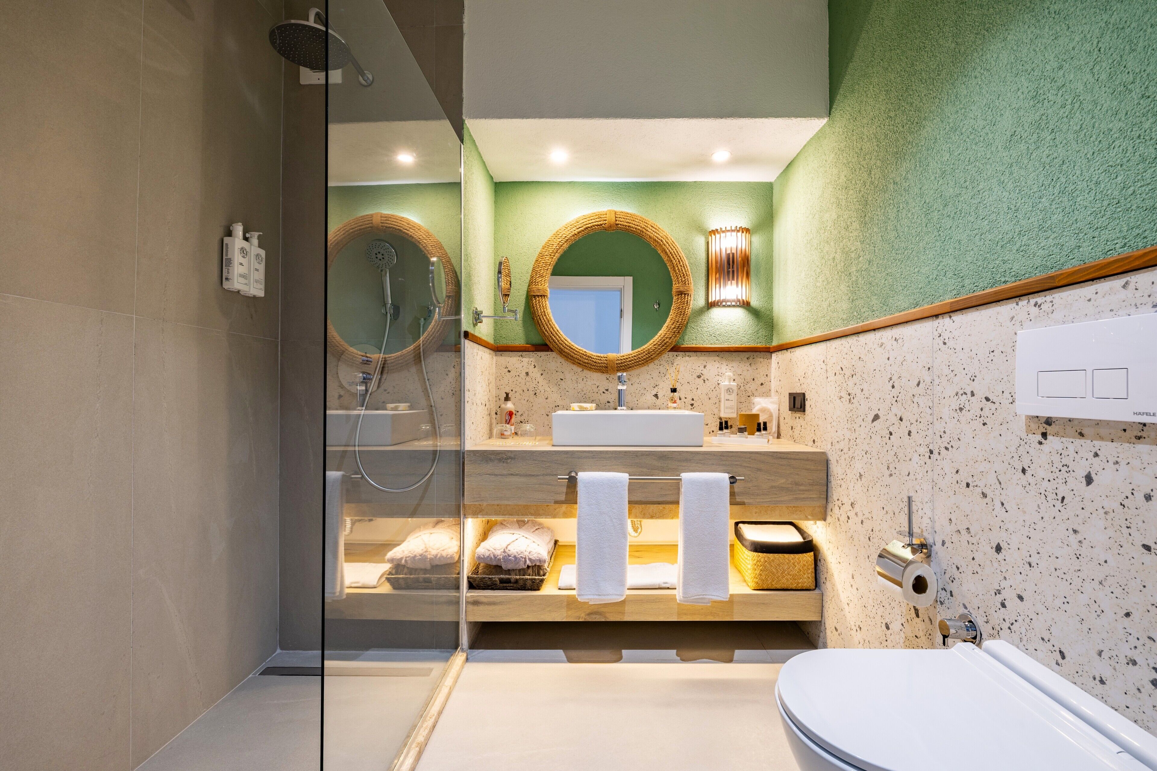 Uma casa de banho moderna com cabine de duche em vidro, uma sanita e uma pia com espelho.