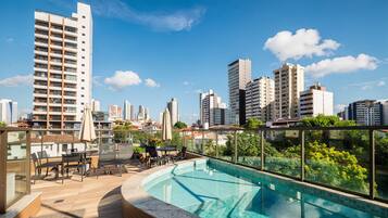 Uma área de piscina no terraço com vista para a paisagem urbana, incluindo edifícios altos e um céu claro.