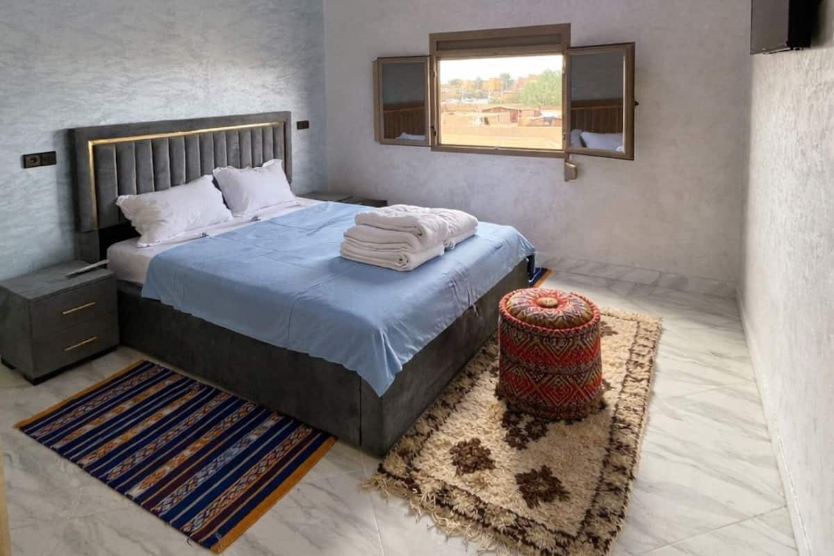 Um quarto moderno com cama, mesas de cabeceira, janela e luminária de teto.