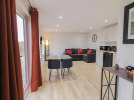 Um espaço de estar moderno com área de refeições, sofá, cozinha e janelas amplas.