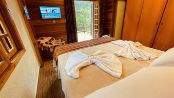 Quarto de hotel com duas camas, televisão na parede e vista para o exterior.