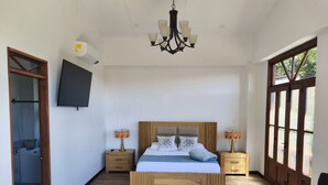 Quarto com cama de madeira, duas mesas de cabeceira com abajures, televisão na parede e uma janela grande.