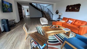 Uma sala de estar moderna com escada, um sofá, uma mesa de centro e uma estante de livros.