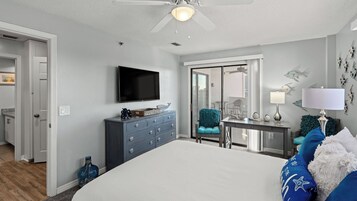 Quarto com cama, cômoda, televisão e escrivaninha com cadeira.