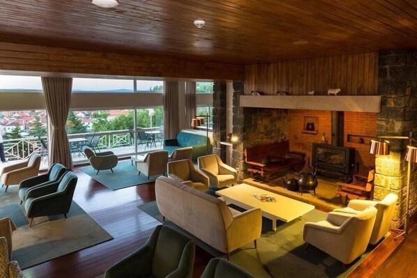 Uma sala de estar espaçosa com lareira, assentos confortáveis e varanda com vista.